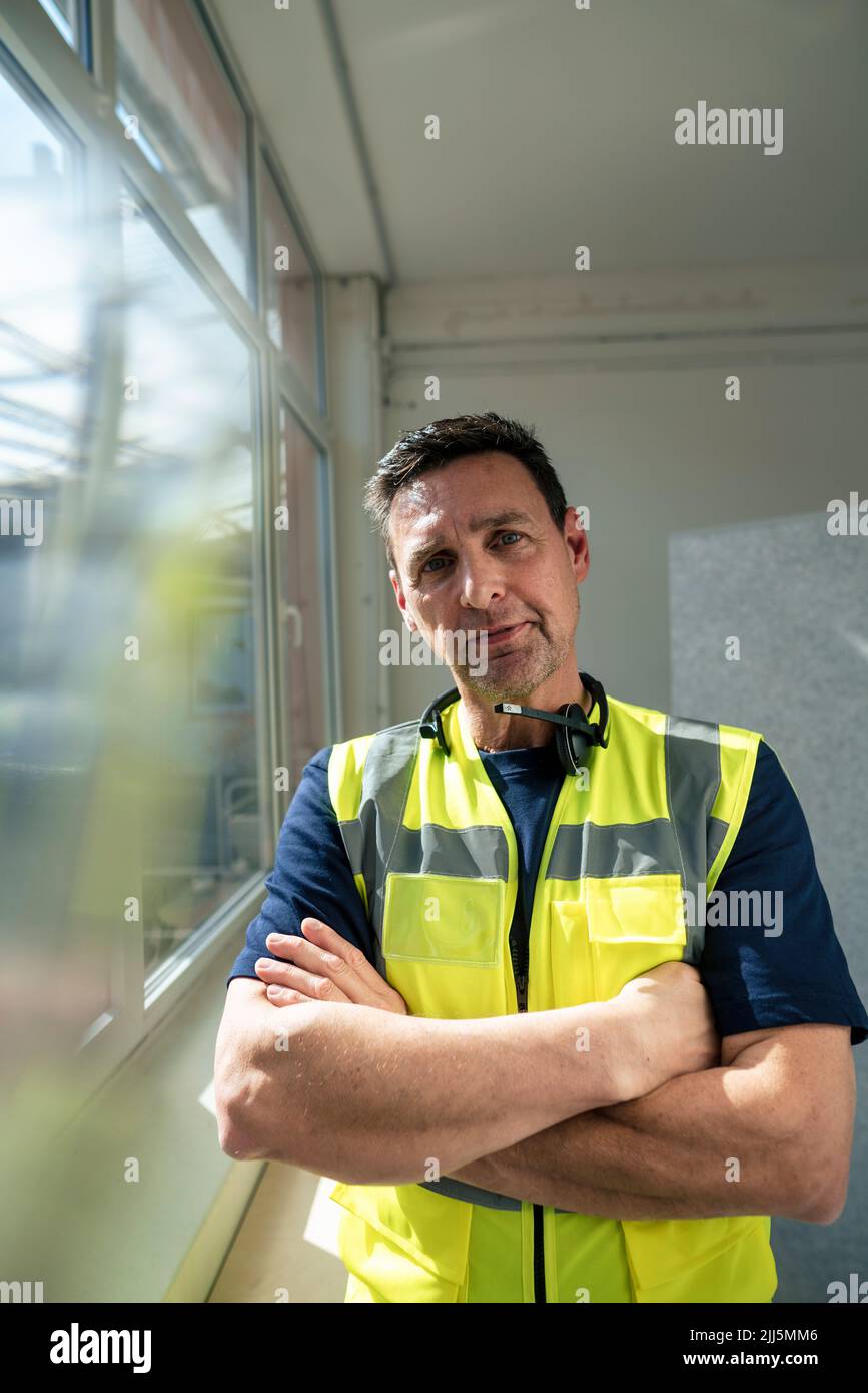 Confident engineer with arms crossed standing by window in office Stock ...