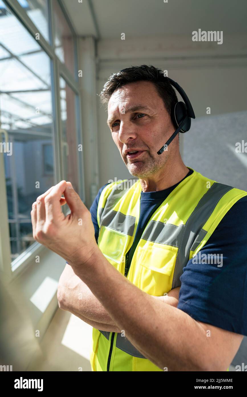 Engineer wearing reflective clothing talking on headset at office Stock ...