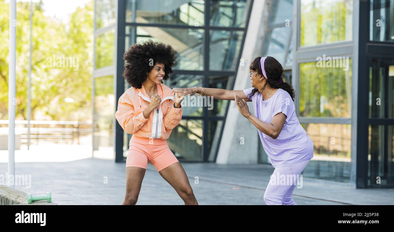 Mother and daughter doing boxing together outside building Stock Photo ...