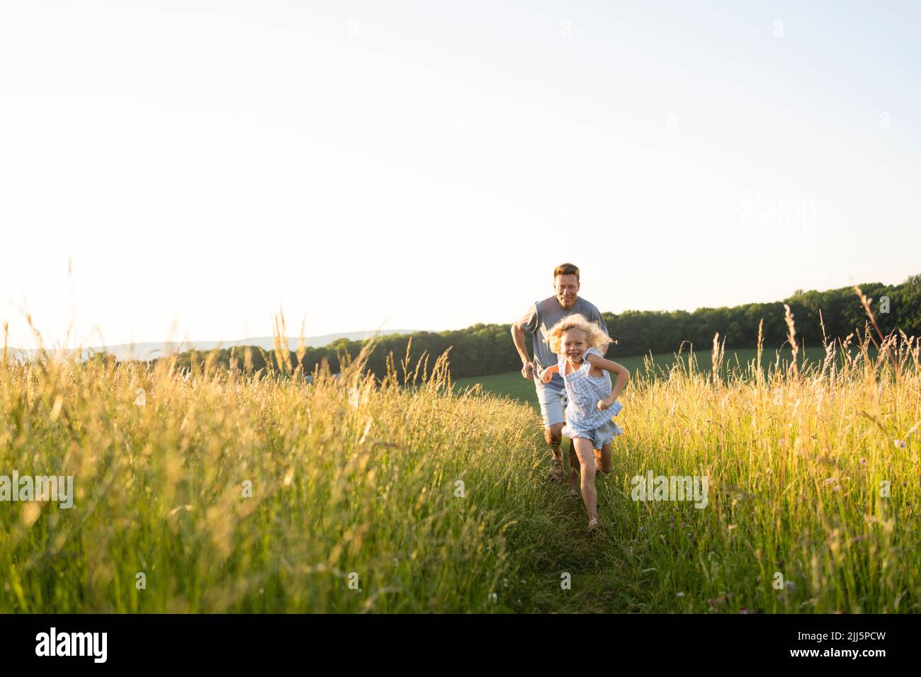 Playful father and daughter running in field Stock Photo - Alamy