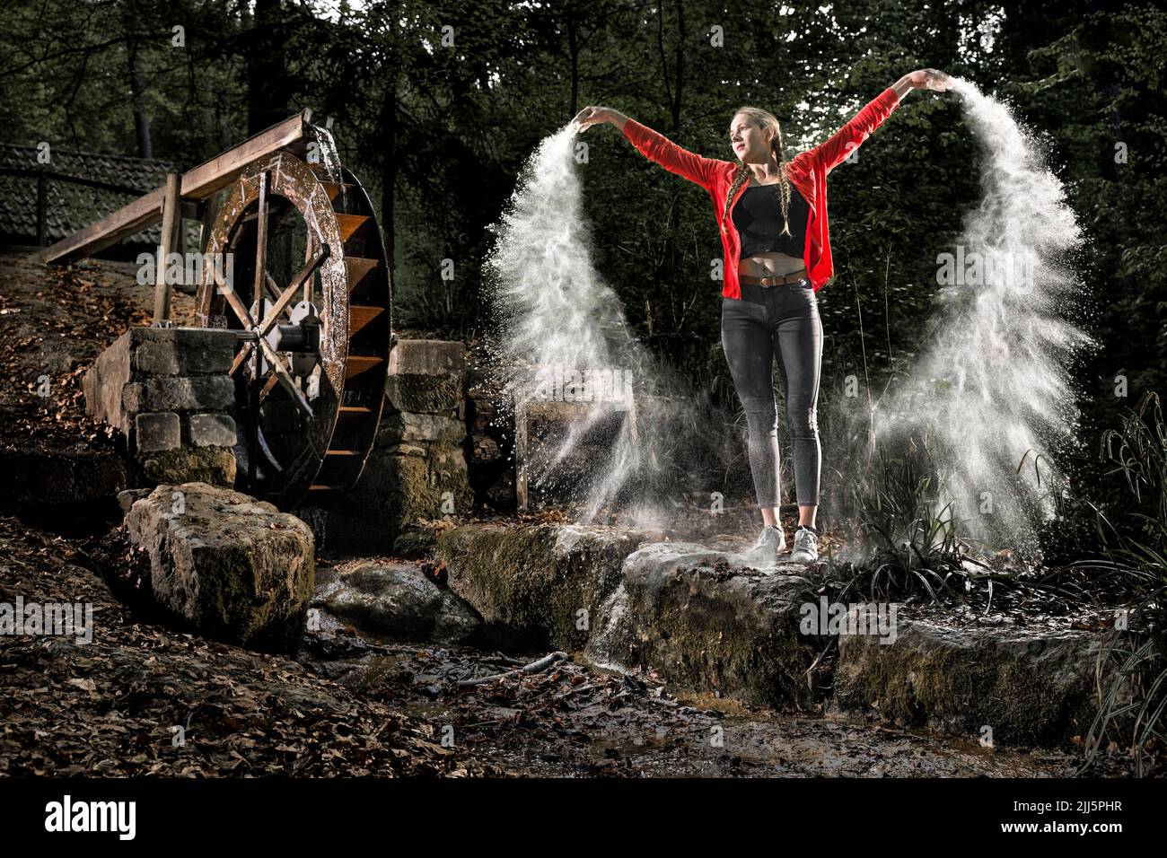 Woman dropping flour standing by water wheel Stock Photo - Alamy