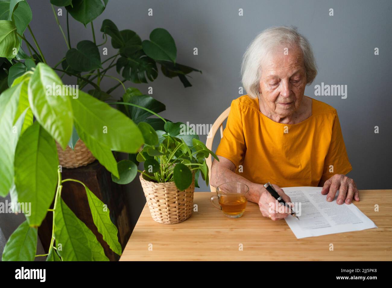 Senior woman with gray hair signing document at home Stock Photo - Alamy