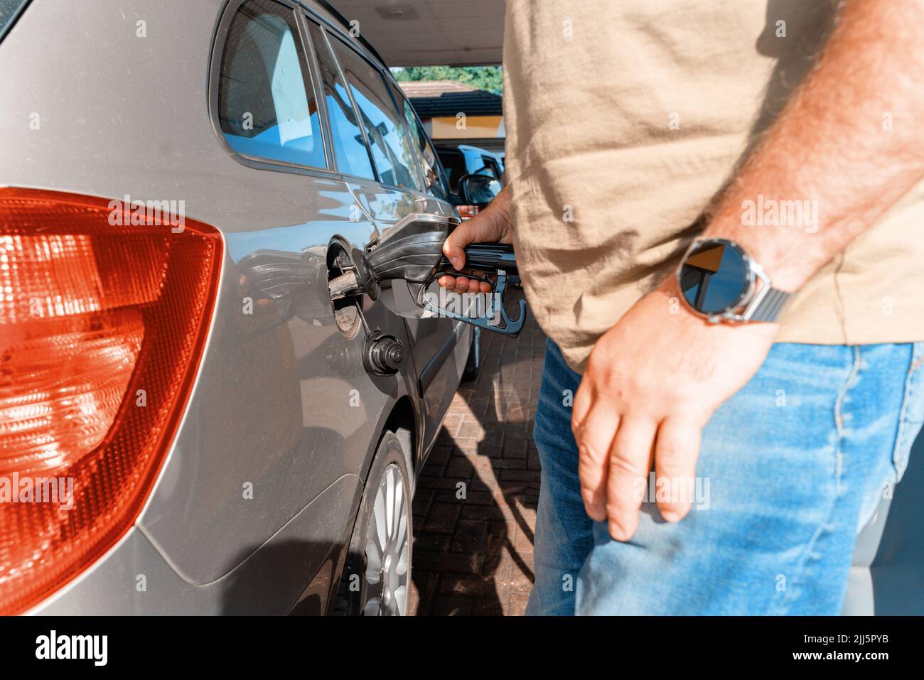 A man at the gas station filling the tank of his car with diesel to the ...