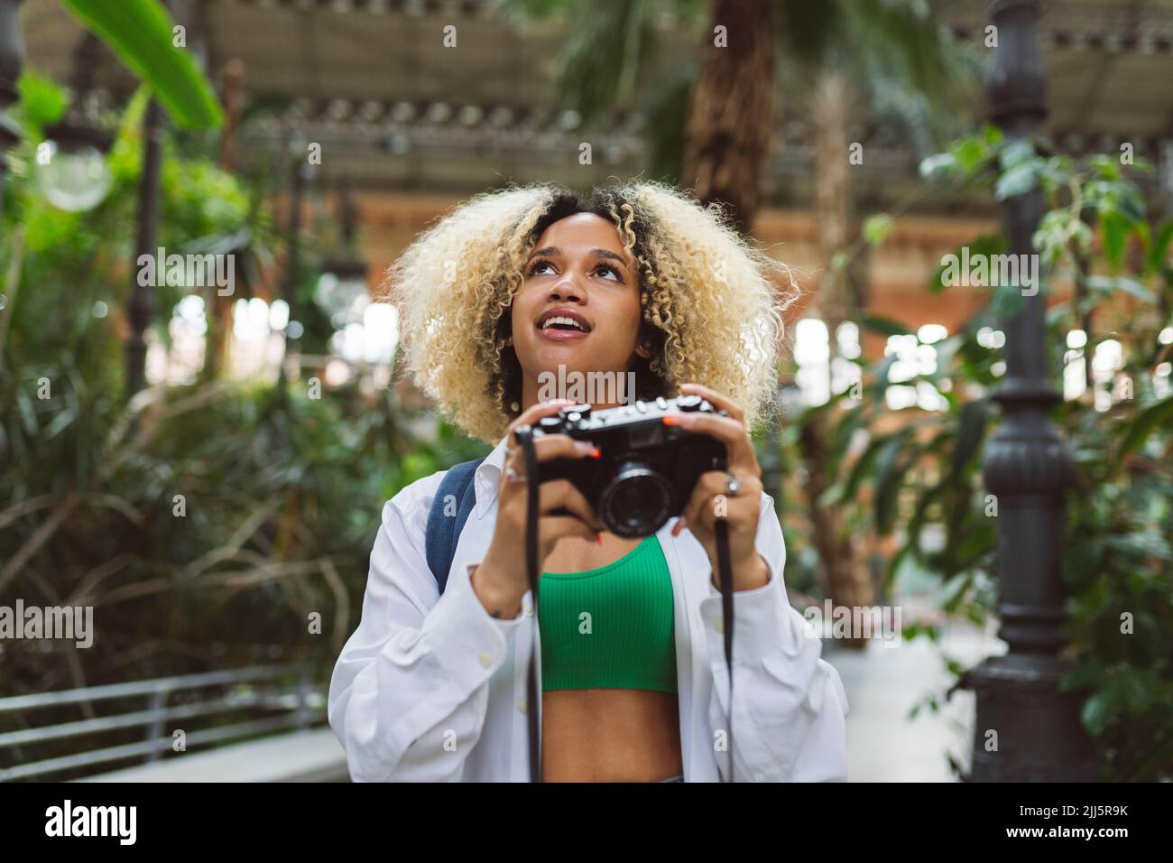 Young woman looking up holding camera Stock Photo - Alamy