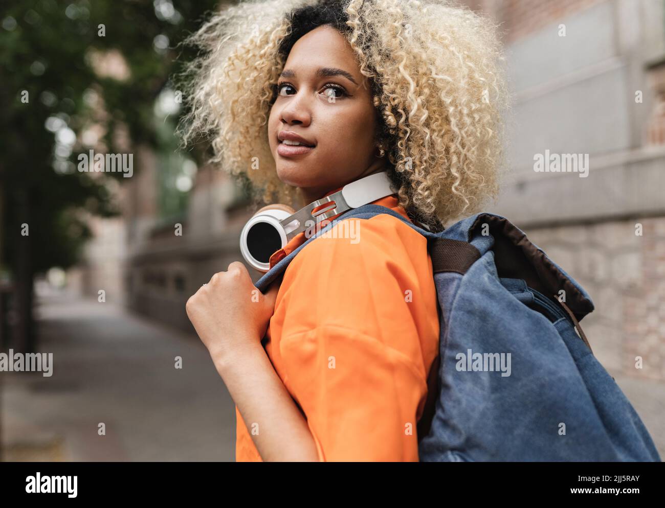 Young woman carrying backpack in front of building Stock Photo - Alamy