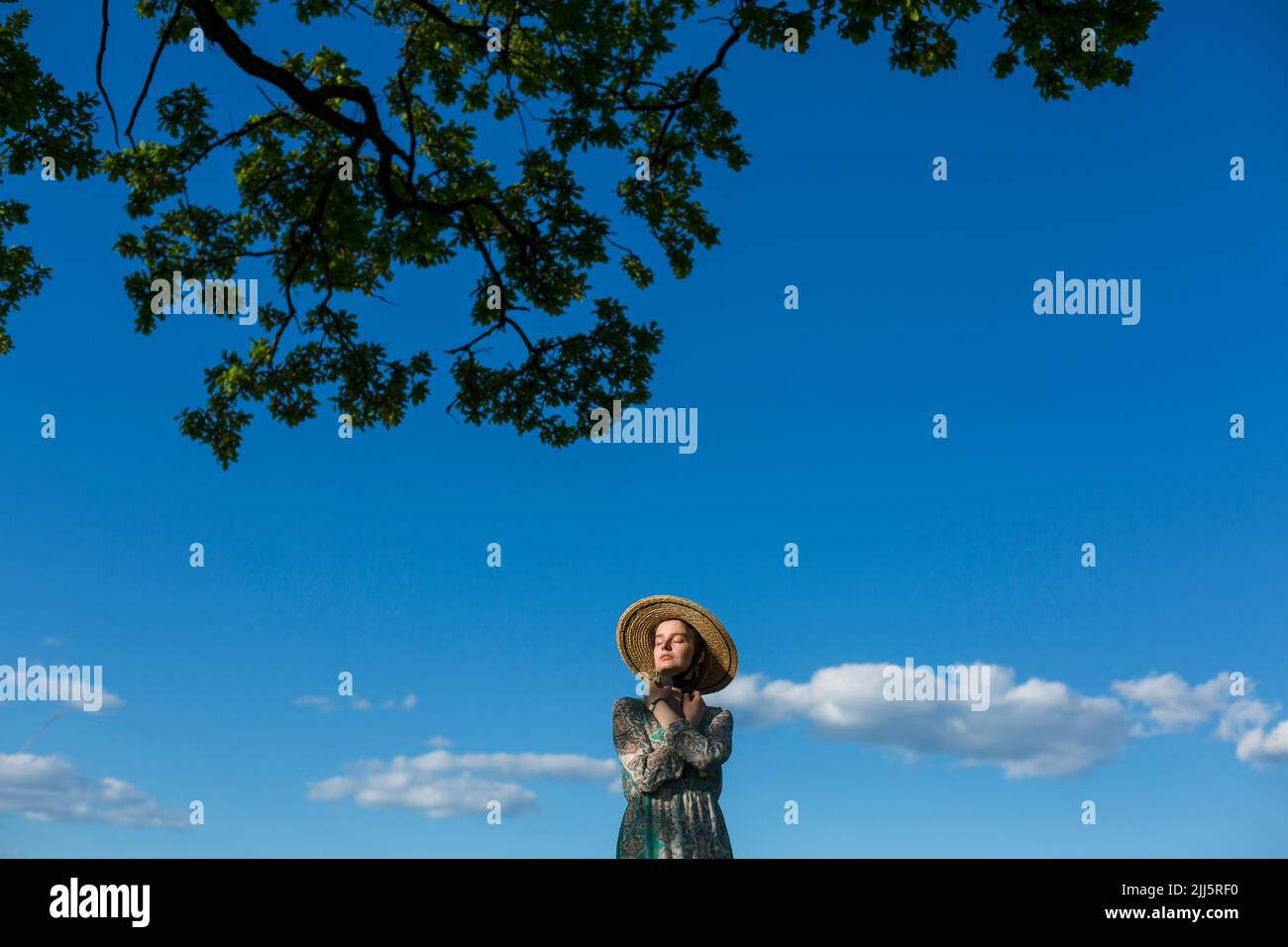 Girl wearing hat standing under tree Stock Photo - Alamy