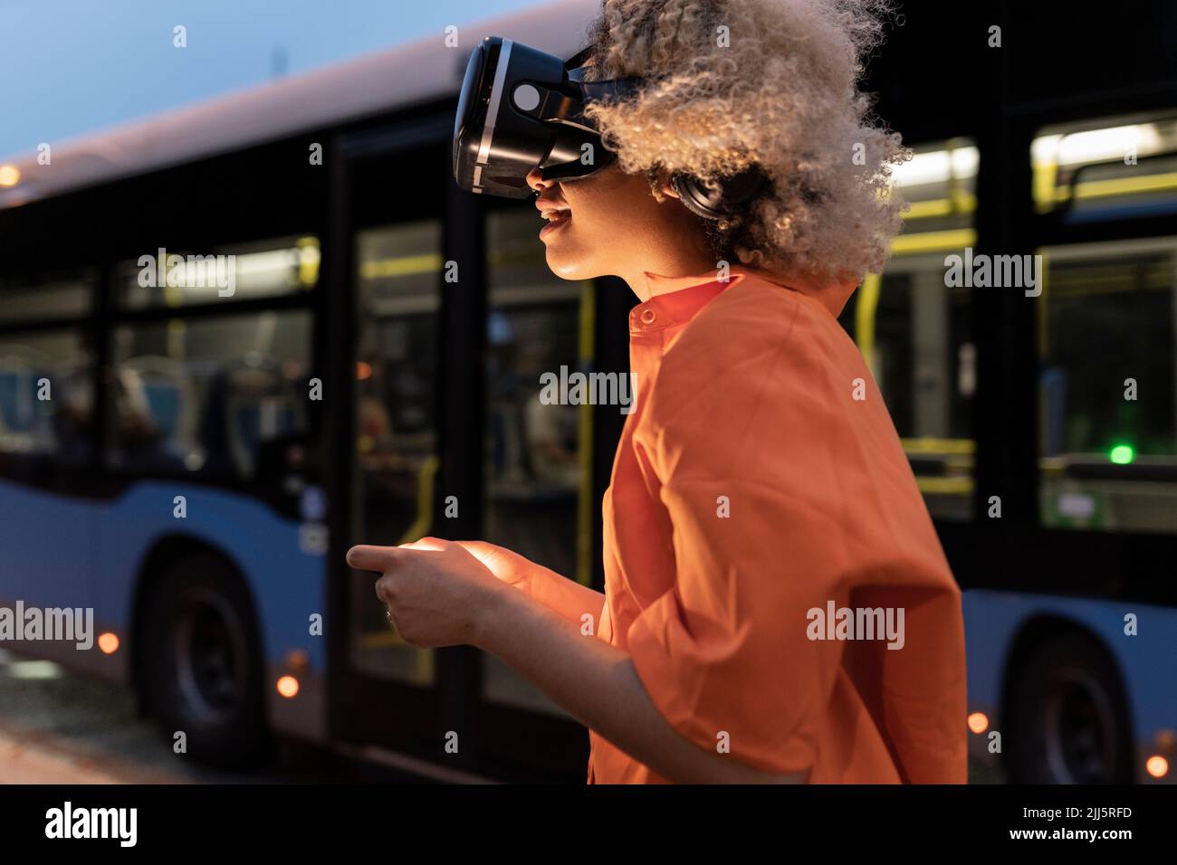Woman enjoying wearing virtual reality headset by bus at night Stock ...