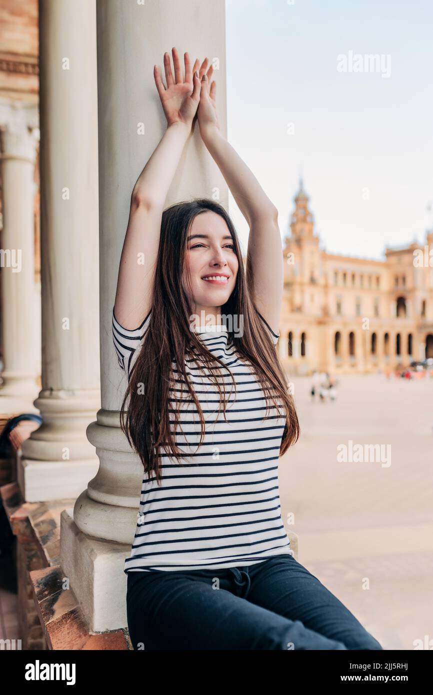 Smiling ballet dancer with arms raised leaning on column Stock Photo ...