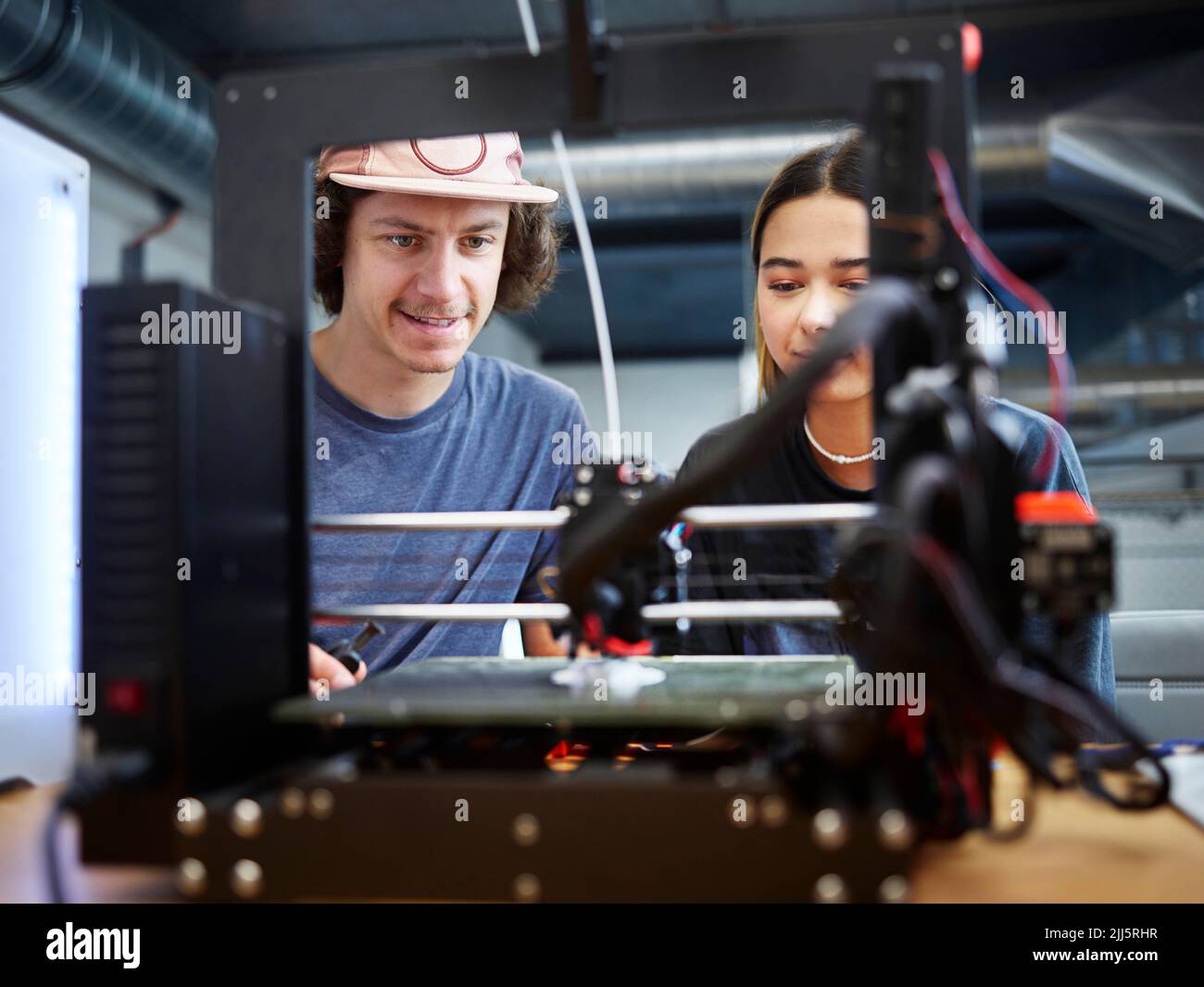 Engineer and colleague operating 3d printer working at workshop Stock ...