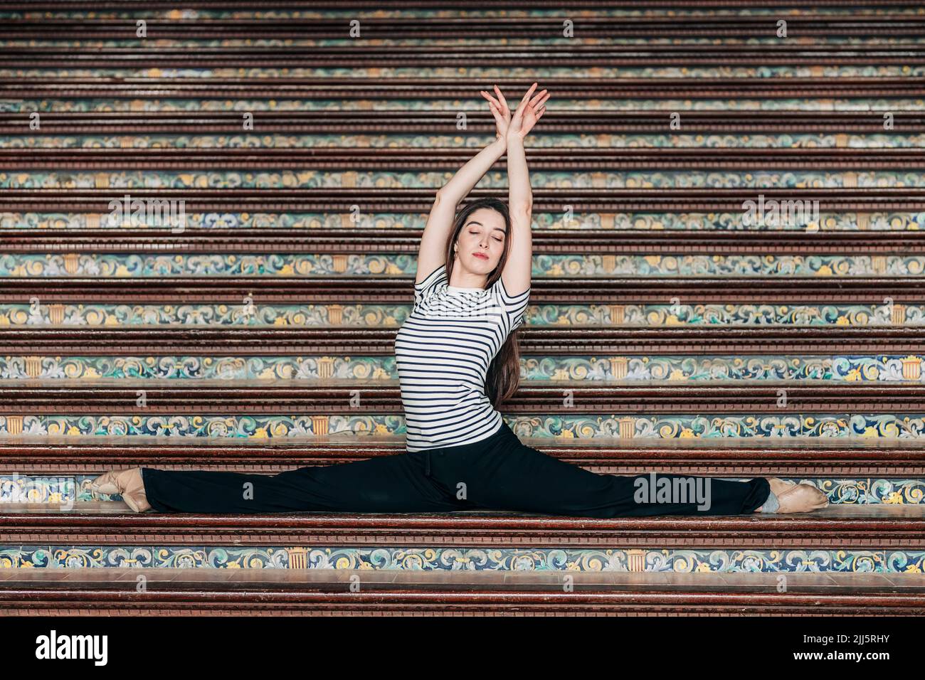 Ballet dancer with arms raised practicing splits on staircase Stock ...