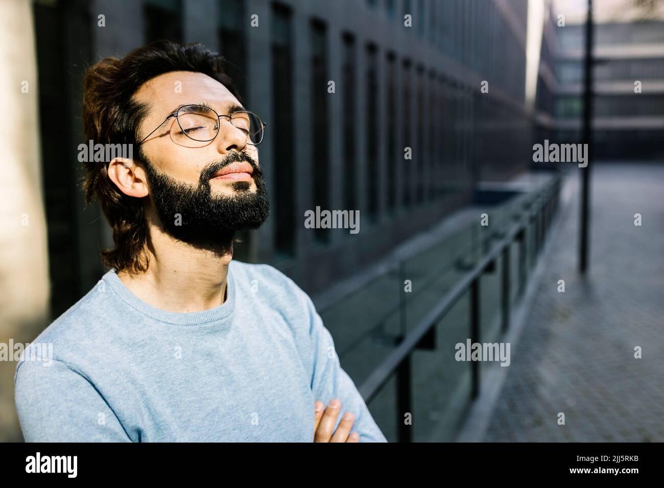 Bearded man with eyes closed in front of building Stock Photo - Alamy