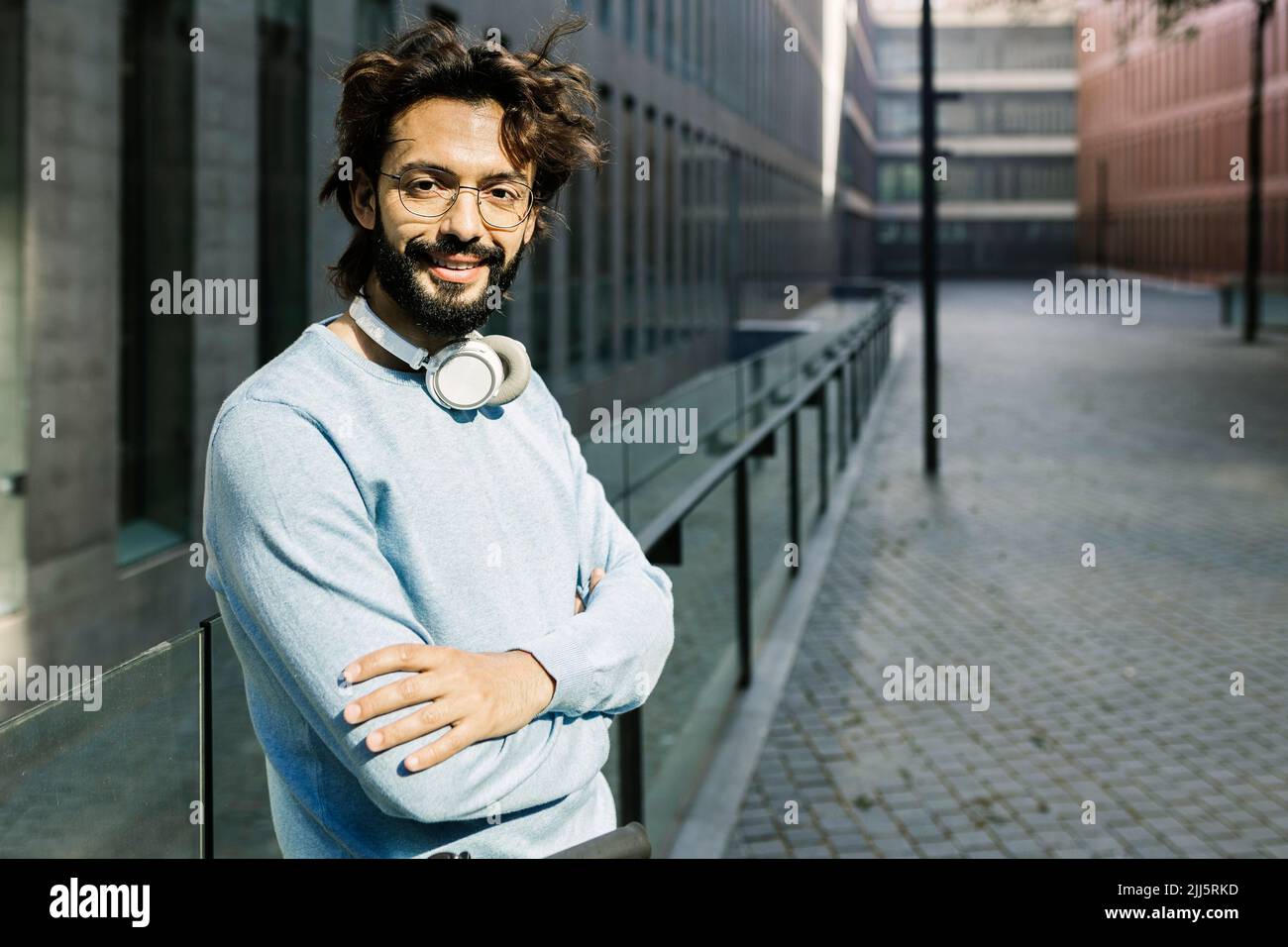 Smiling mam with arms crossed leaning on railing Stock Photo - Alamy
