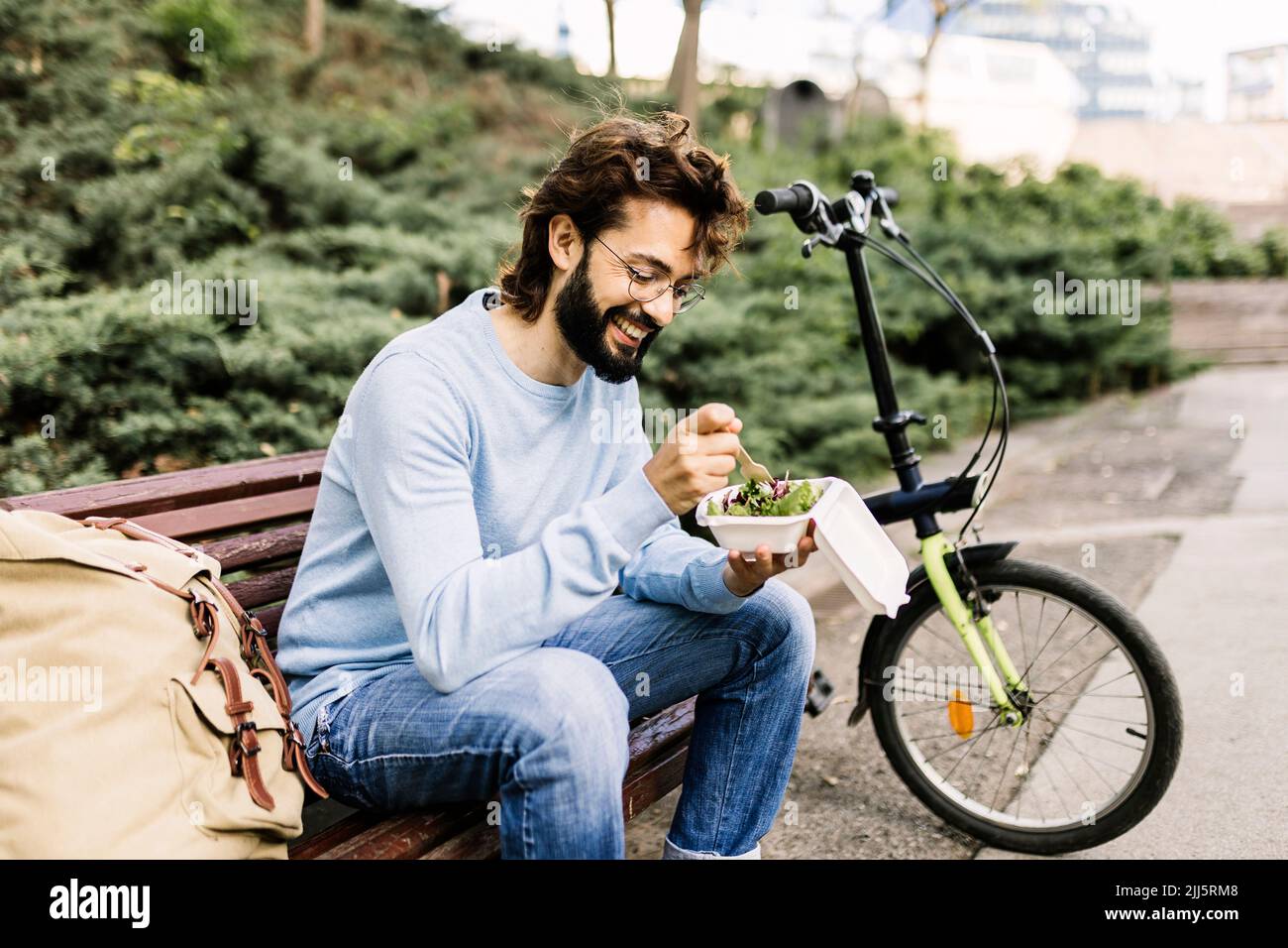 Happy man with food sitting on bench Stock Photo - Alamy