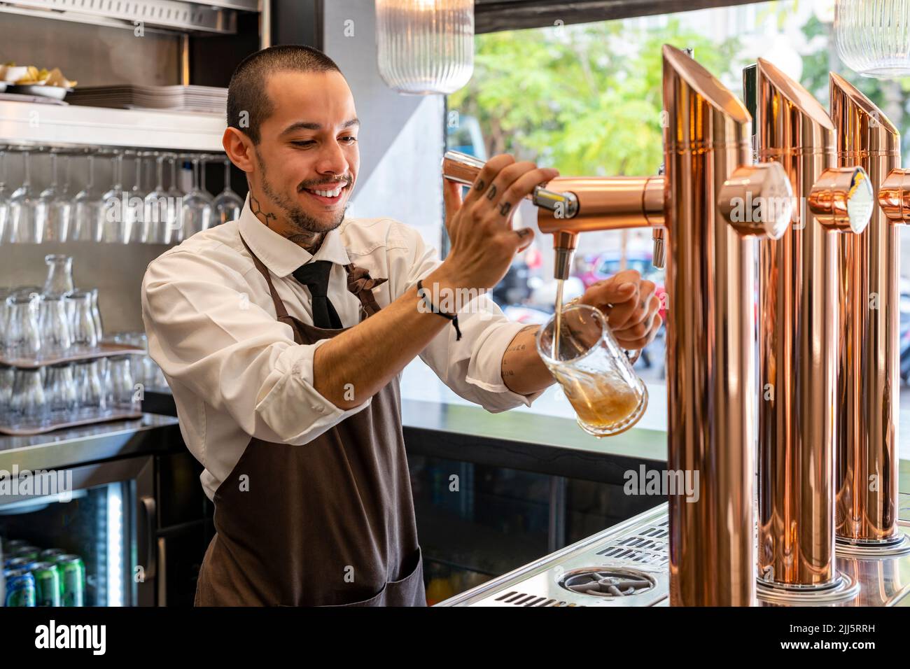 Bartender filling beer in glass from tap at bar Stock Photo - Alamy