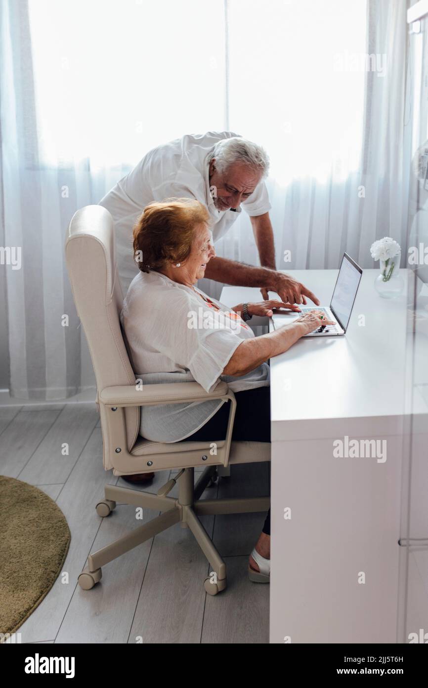 Man explaining laptop to senior woman at home Stock Photo - Alamy