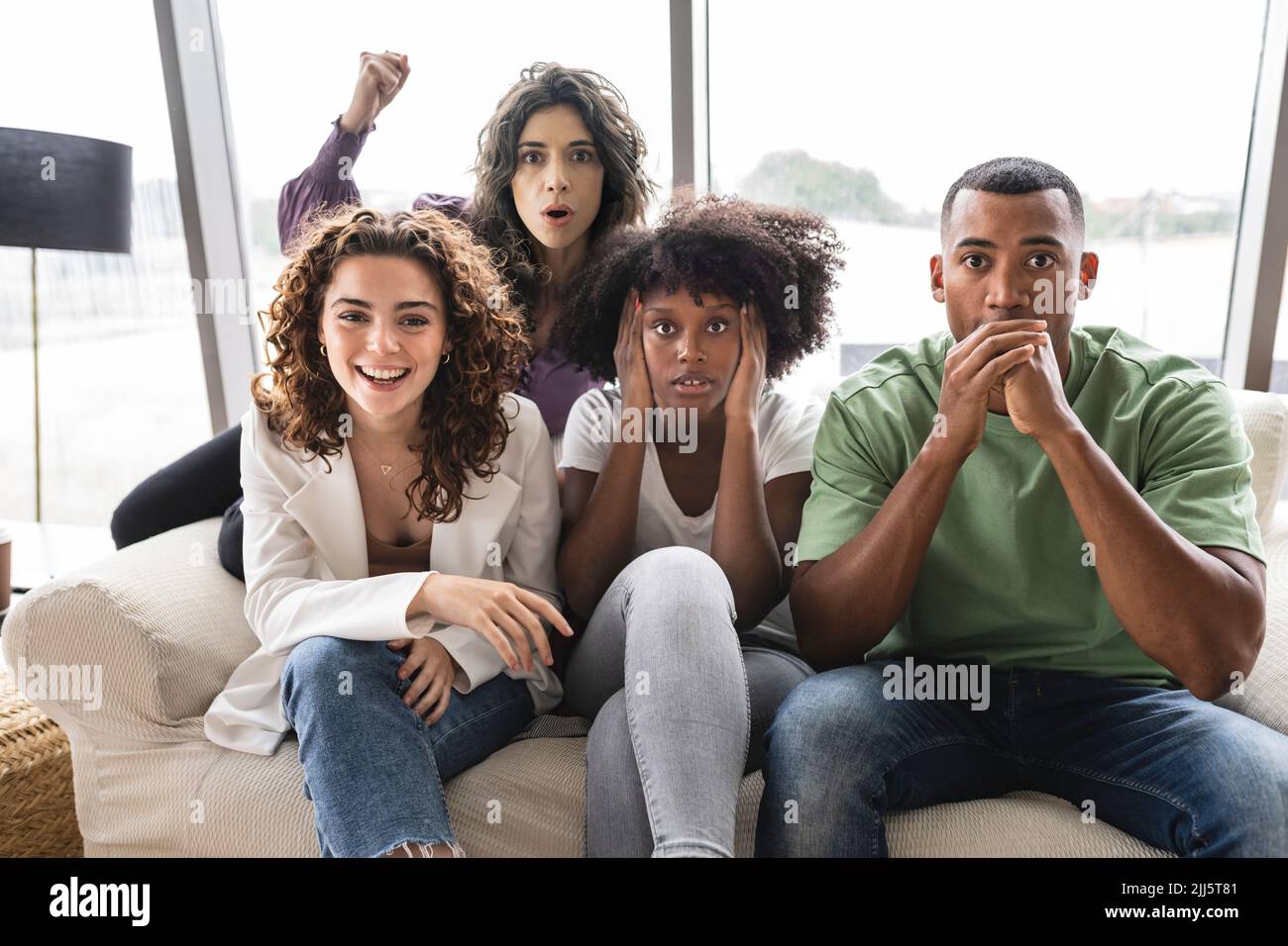 Excited friends sitting on sofa together Stock Photo - Alamy