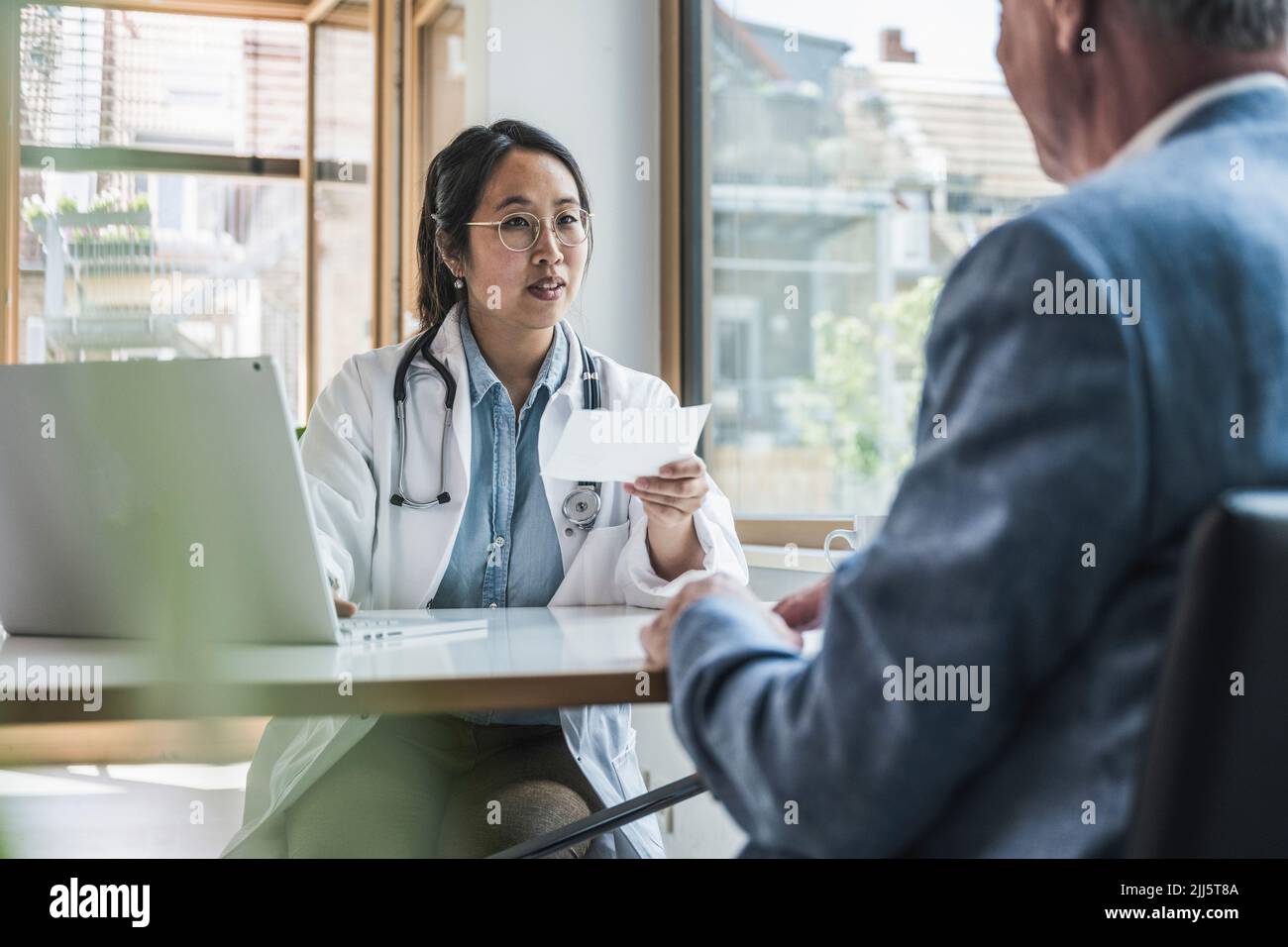 Doctor discussing with patient over prescription in medical clinic ...