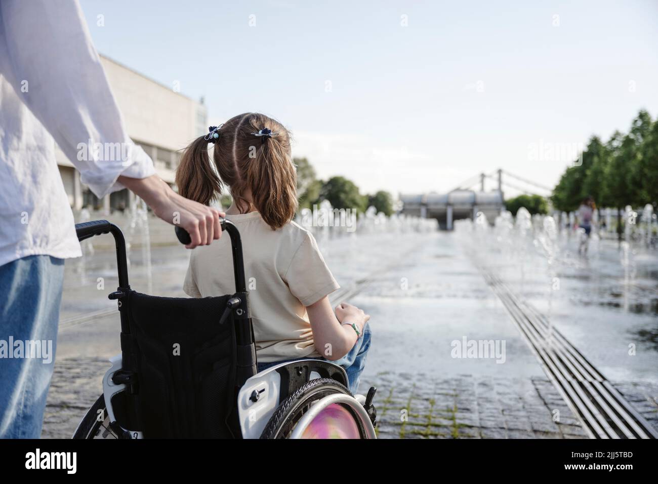 Mother standing behind daughter with disability sitting in wheelchair ...