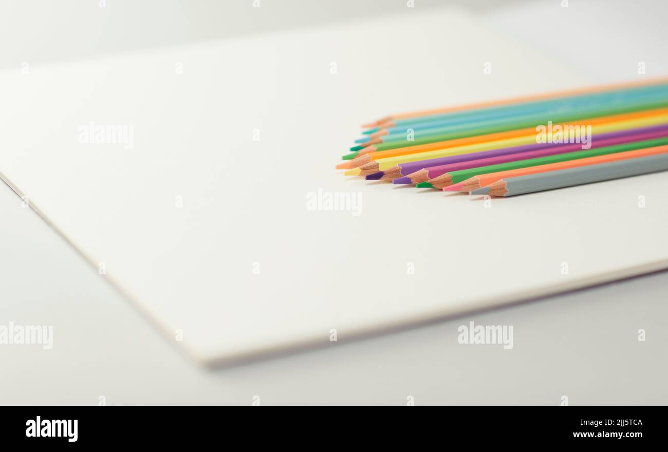 Studio shot of row of colored pencils lying on top of drawing paper ...
