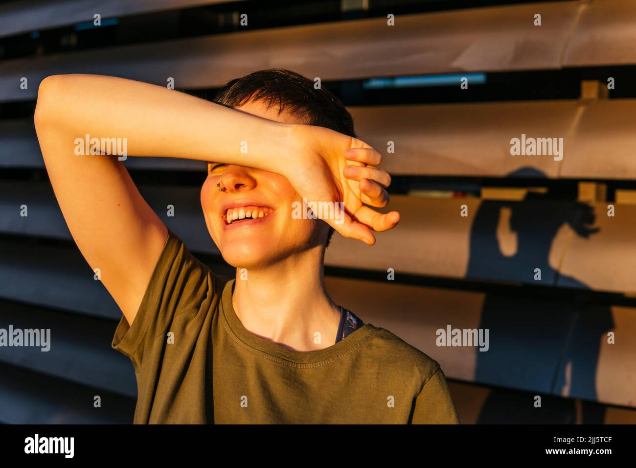 Happy woman with short hair covering face with hand Stock Photo - Alamy