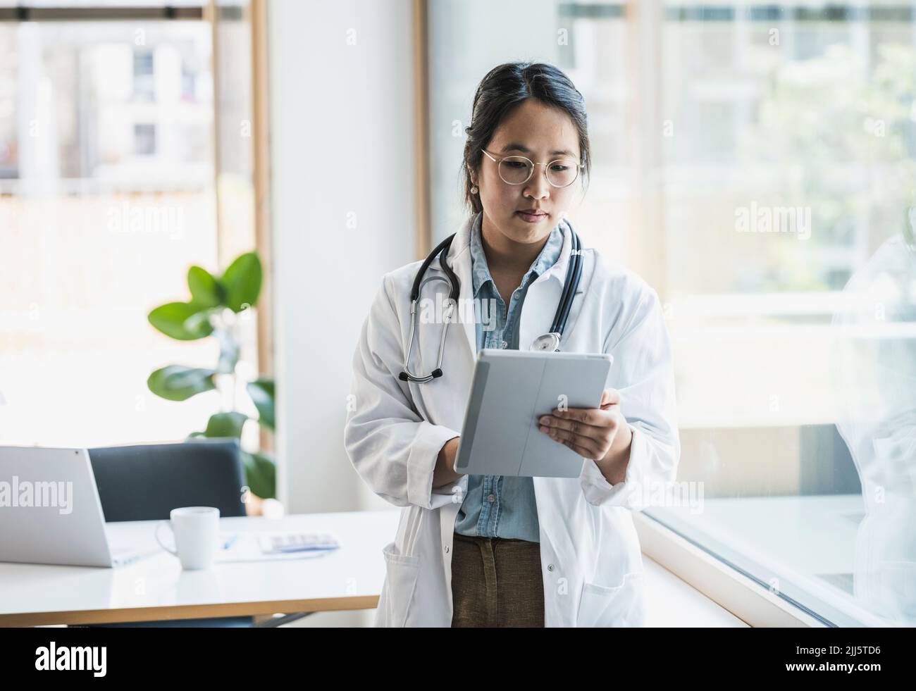 Female doctor using tablet PC by window at hospital Stock Photo - Alamy