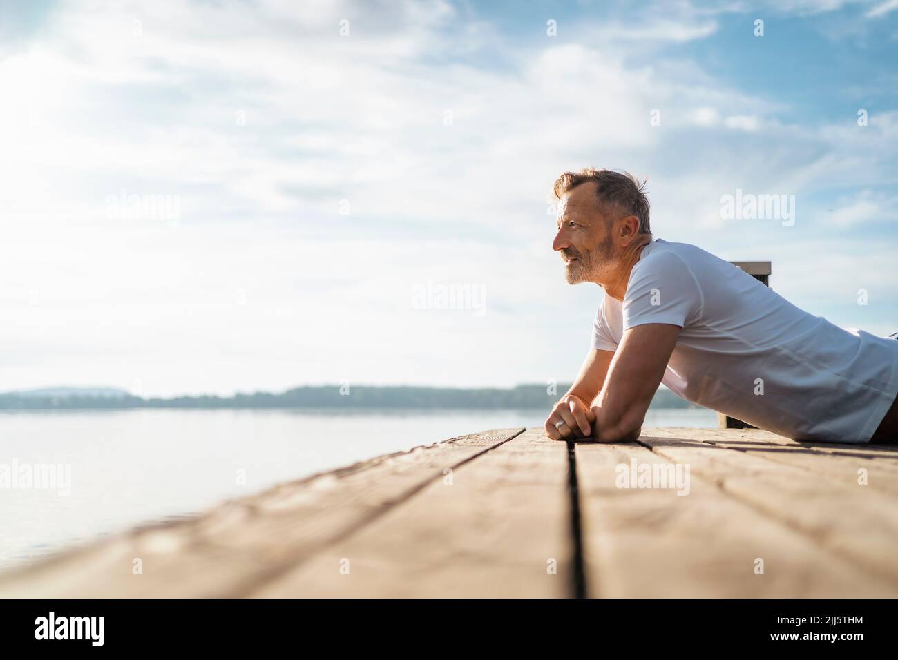 Mature man leaning on elbows at pier Stock Photo - Alamy