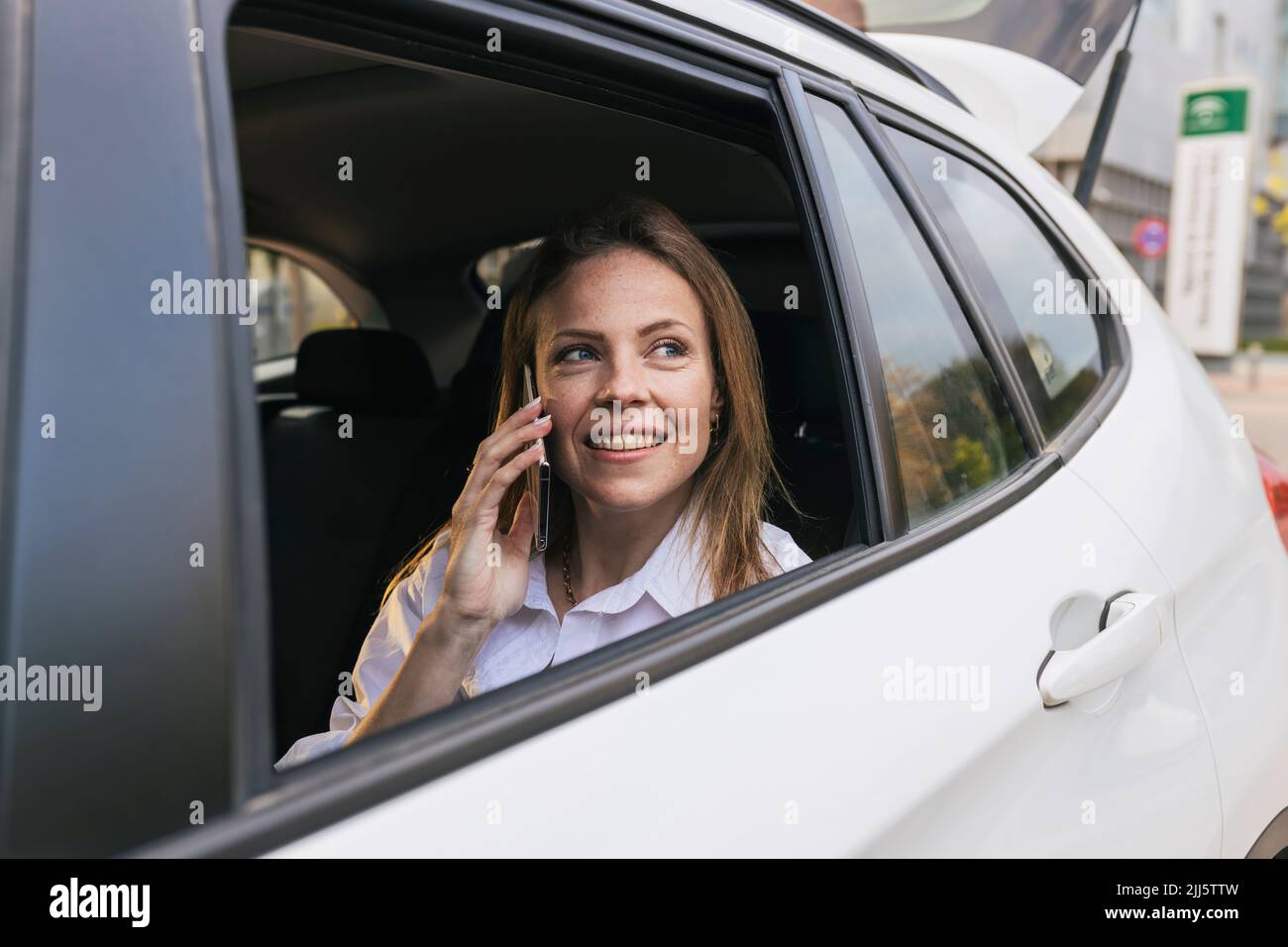 Smiling businesswoman talking on phone looking through car window Stock ...