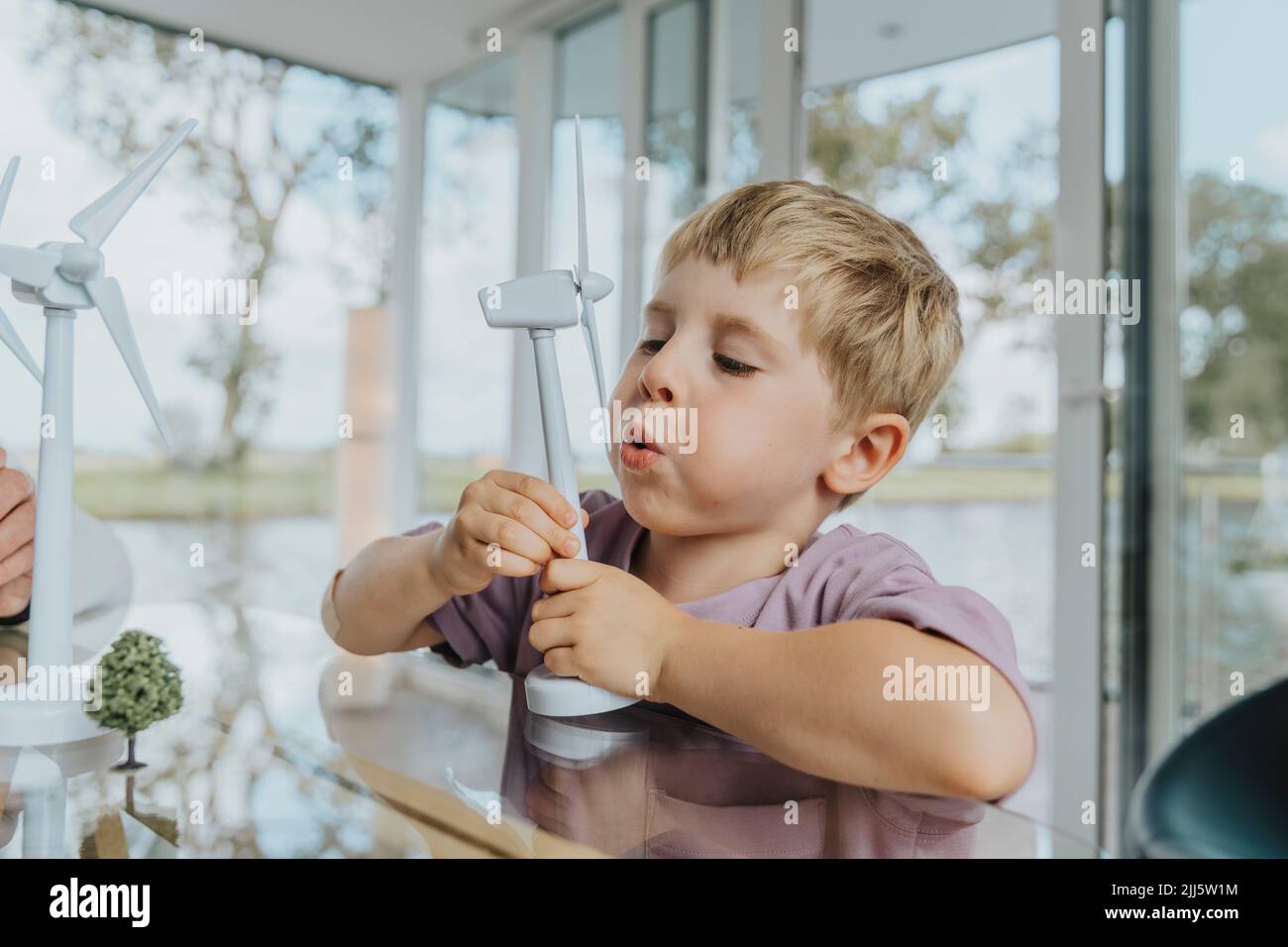 Boy blowing on wind turbine model at home Stock Photo - Alamy