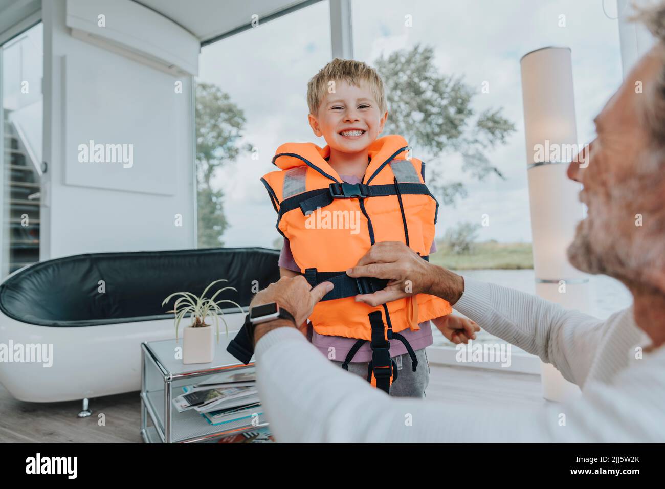 Happy son with father adjusting life jacket at home Stock Photo - Alamy