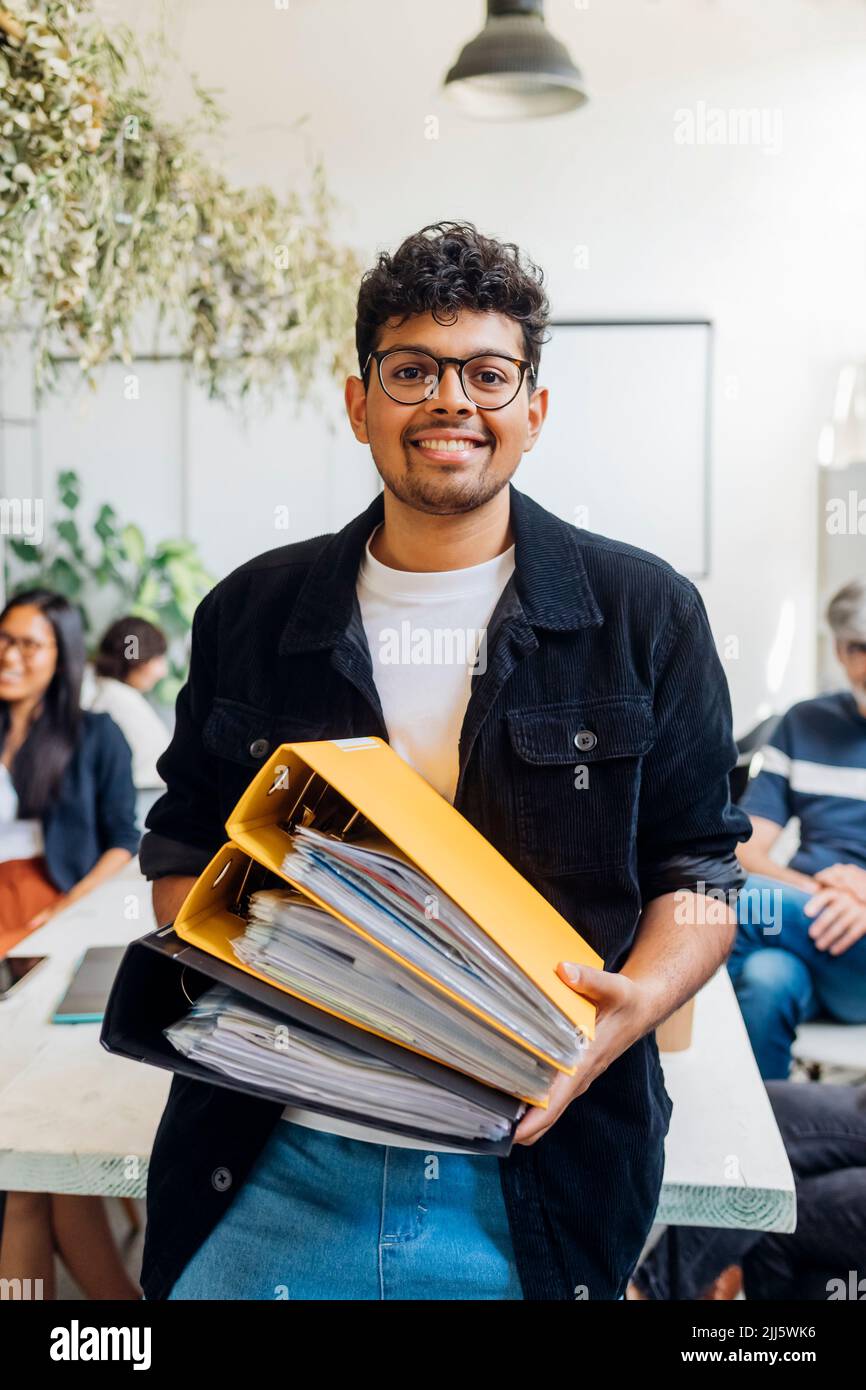 Smiling businessman holding files at workplace Stock Photo - Alamy