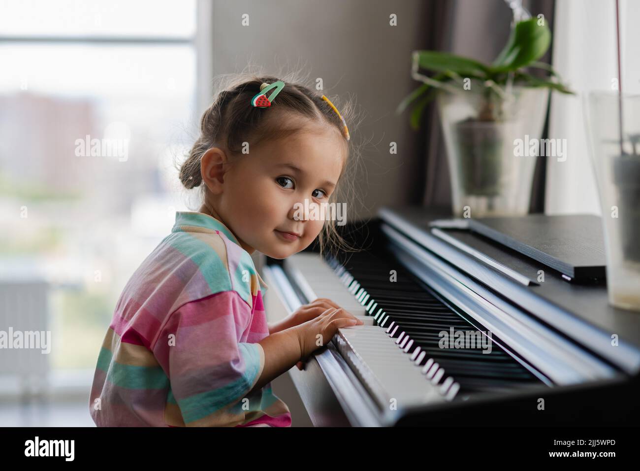 Cute little girl playing piano at a music school. Preschool child ...