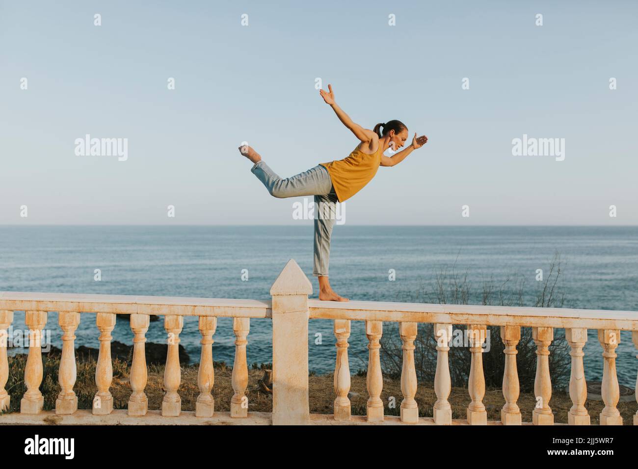 Woman balancing on railing at the sea Stock Photo - Alamy