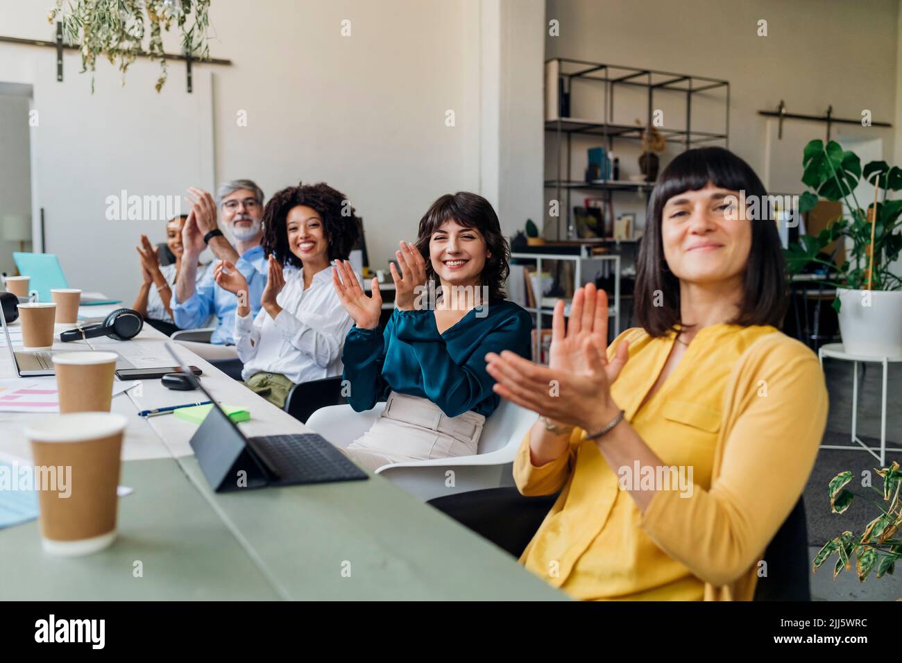 Smiling multiracial colleagues clapping hands in meeting at office ...