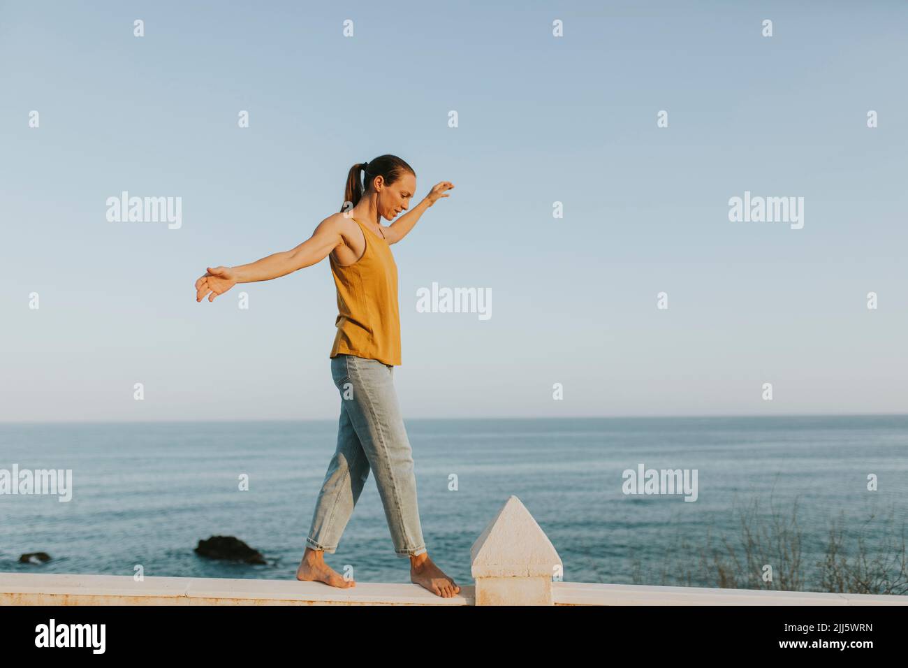 Woman balancing on railing at the sea on sunny day Stock Photo - Alamy