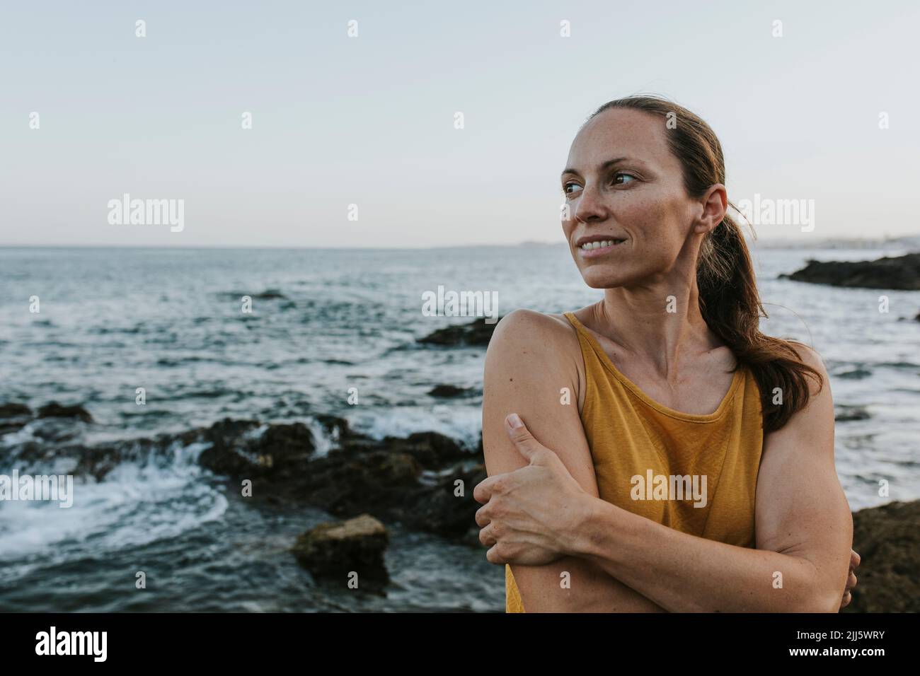 Happy woman hugging self at sea shore on sunset Stock Photo - Alamy