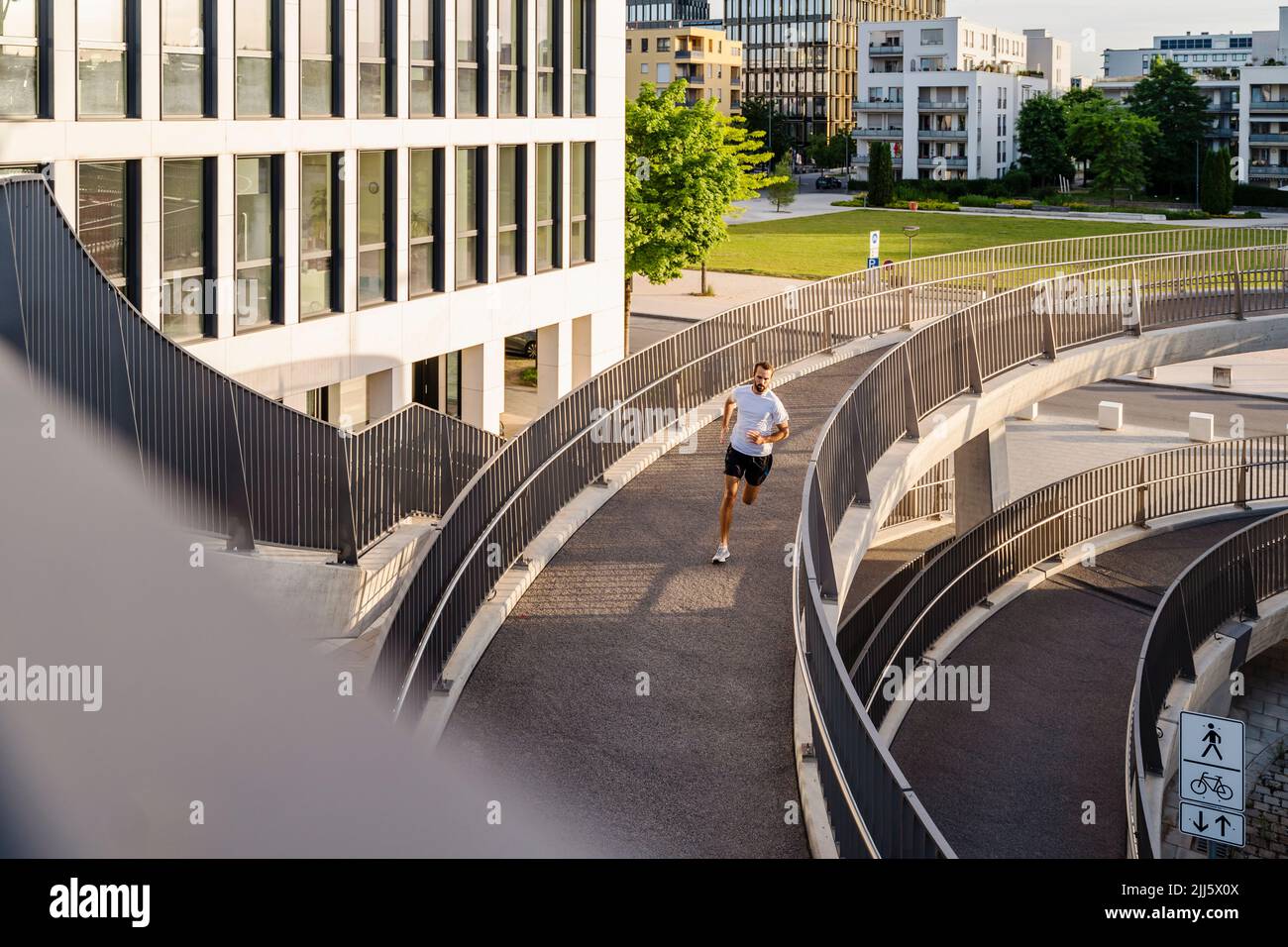 Young man running on elevated walkway Stock Photo - Alamy