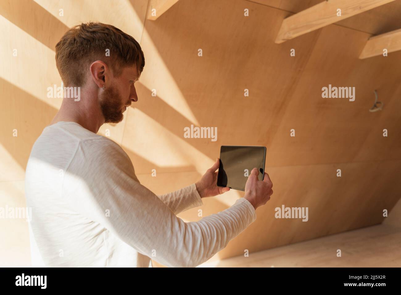 Man using tablet pc to visualise home interior at new wooden eco house ...