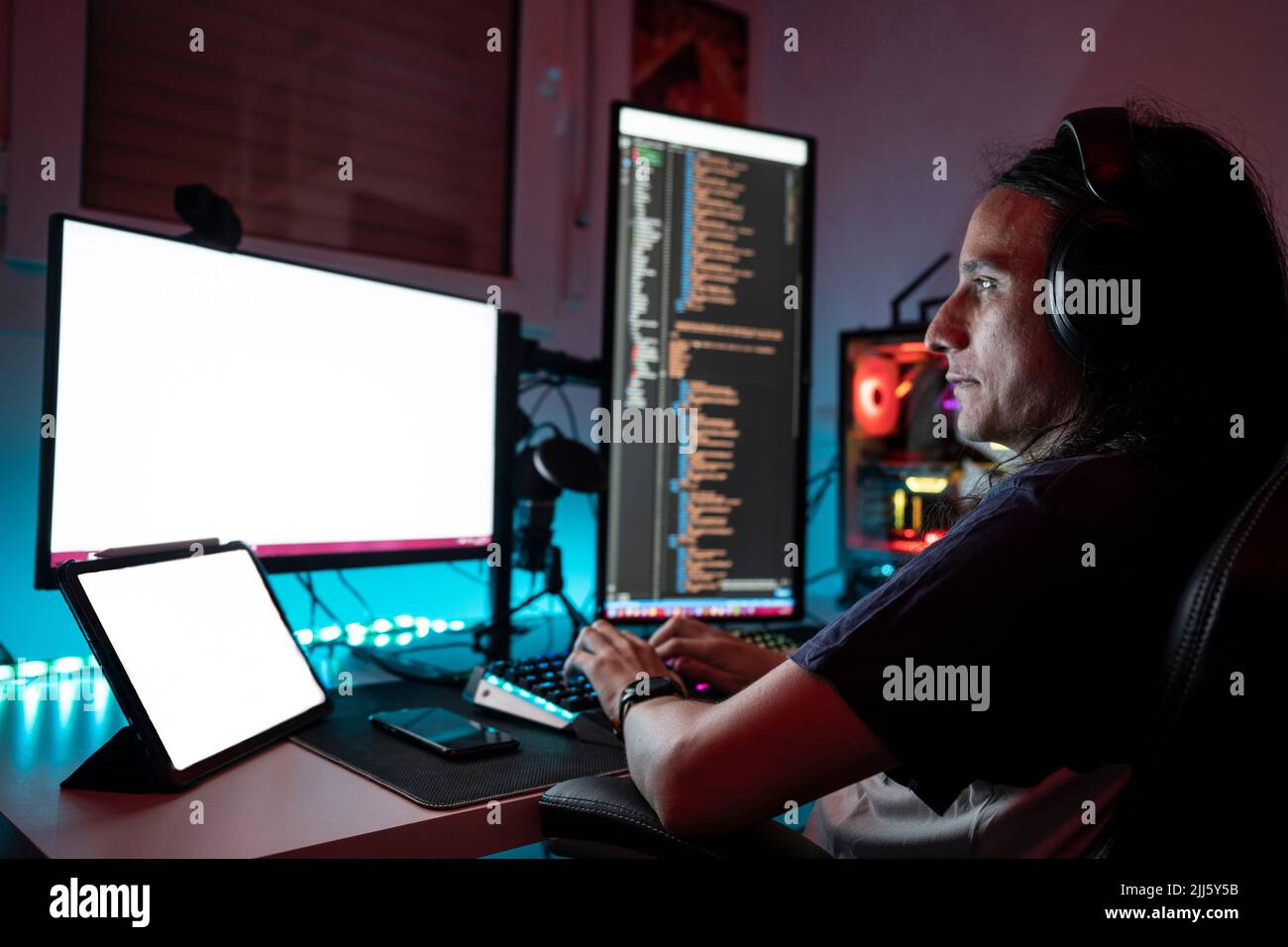 Man wearing headphones using computer at home Stock Photo - Alamy