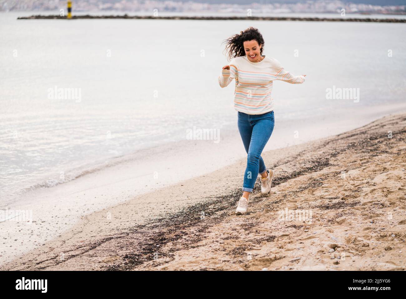 Cheerful woman running on sand at beach Stock Photo - Alamy