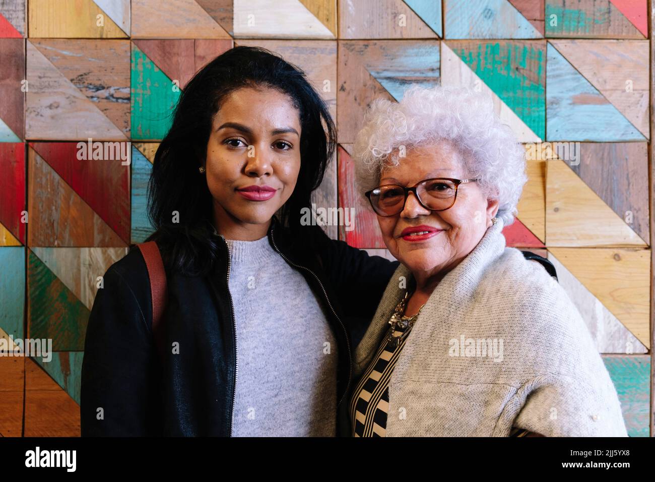 Confident daughter with mother standing in front of wall Stock Photo ...