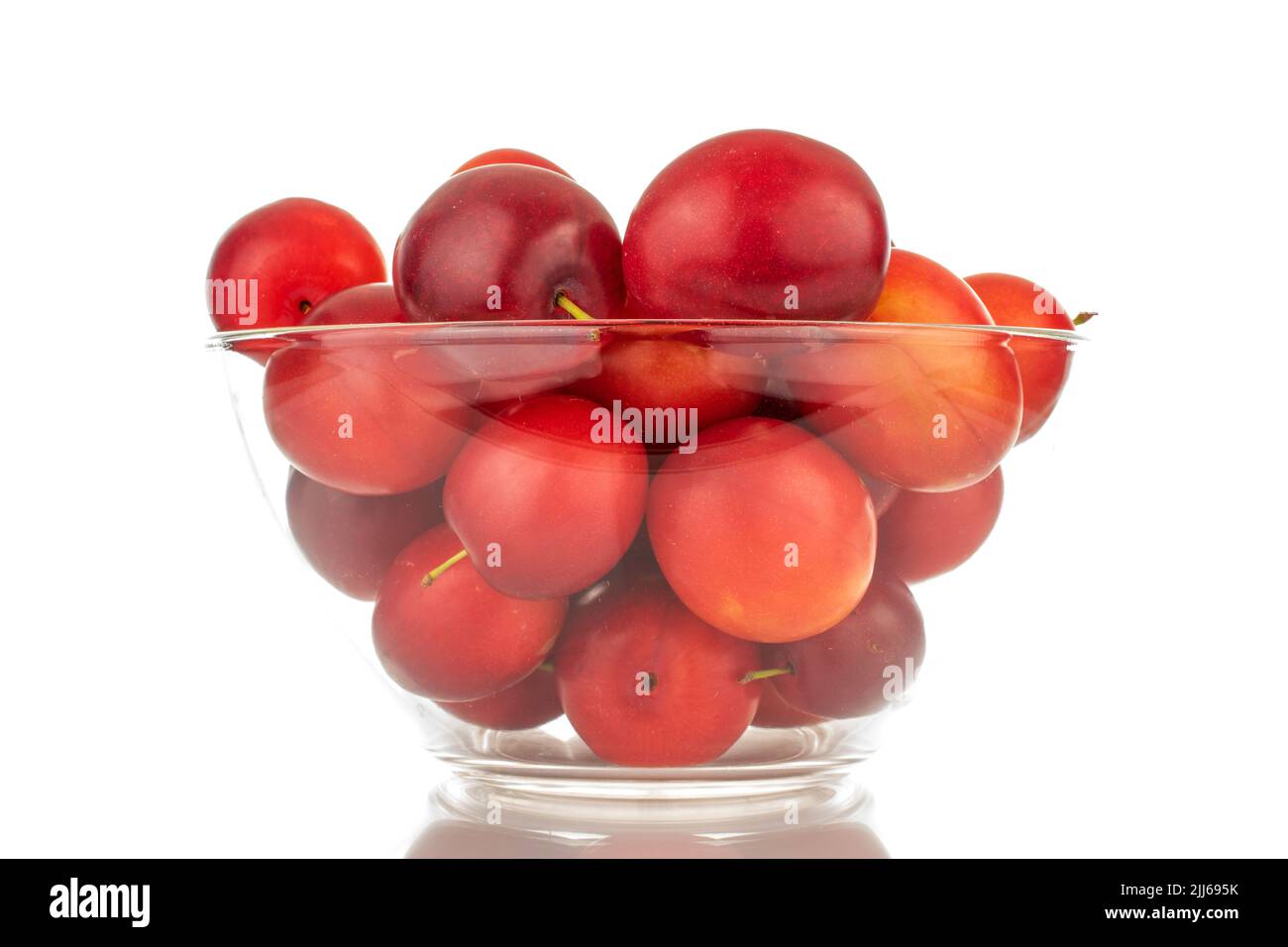 Several ripe juicy cherry plums in a glass dish, close-up, isolated on ...