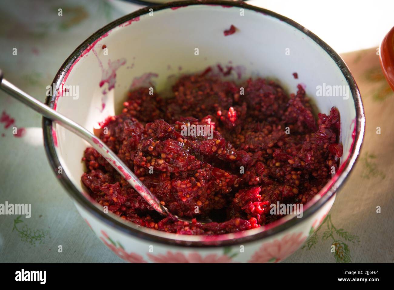 Woman prepares jam of the raw red currants, female makes marmalade for ...