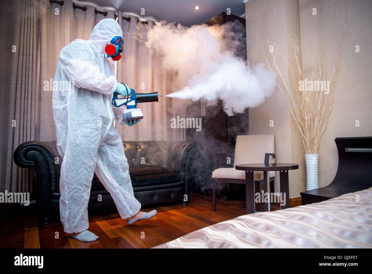 disinfection of the room against viruses. Man in quarantine clothes ...