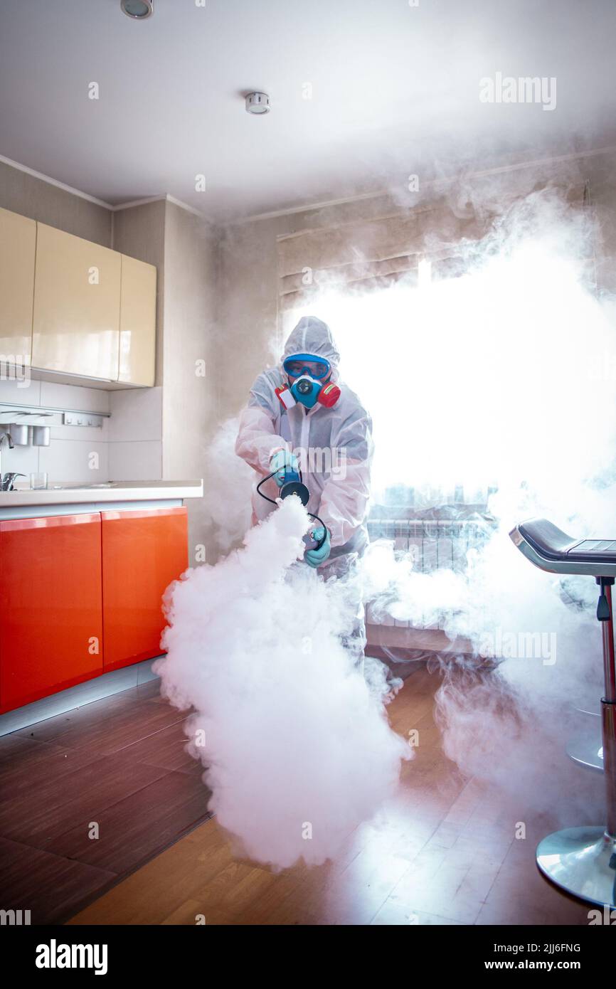 disinfection of the room against viruses. Man in quarantine clothes ...