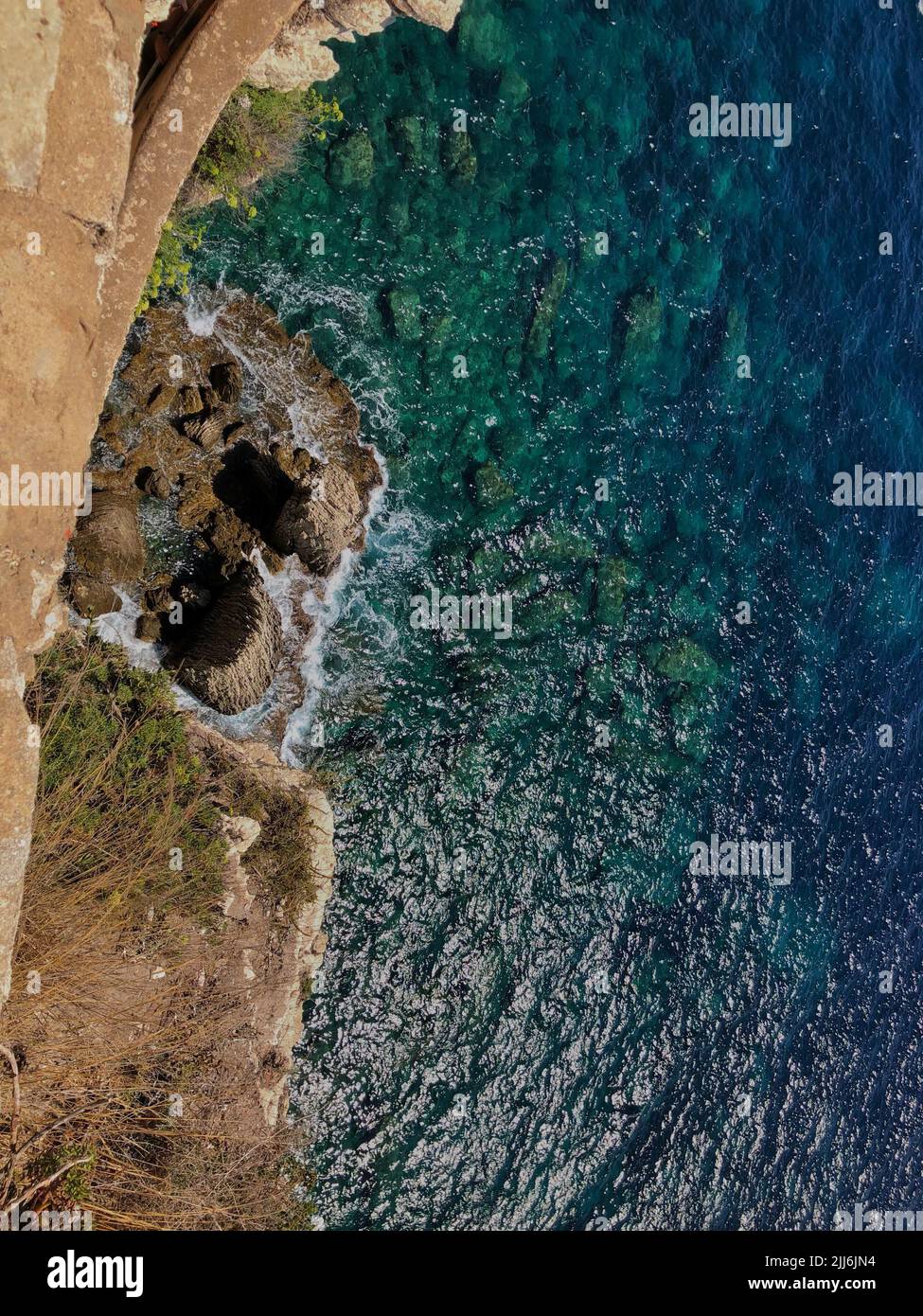 An aerial view of rocks and blue water on the shore Stock Photo - Alamy