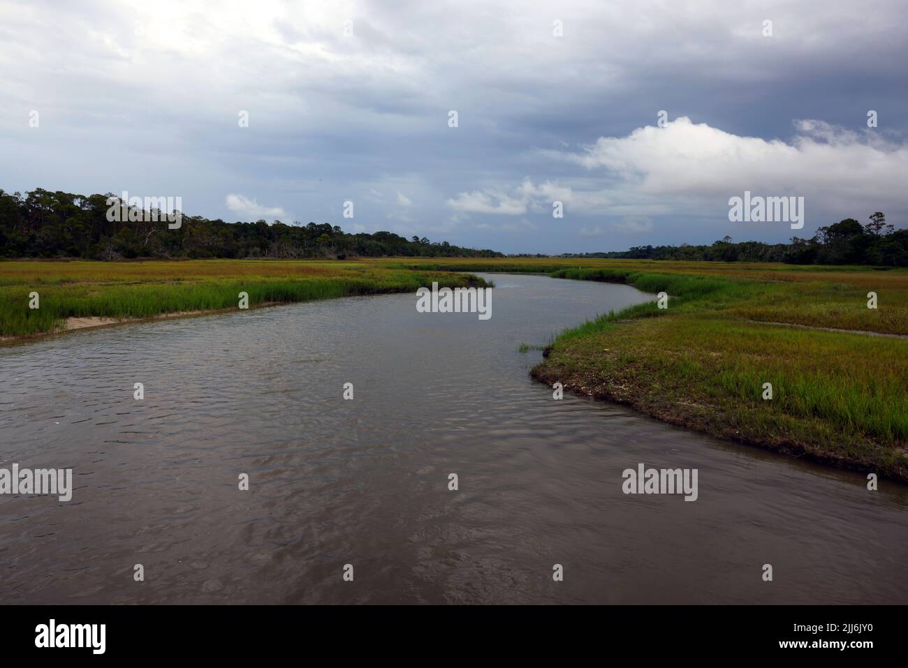 A curvy river in a green field with a cloudy sky background Stock Photo ...