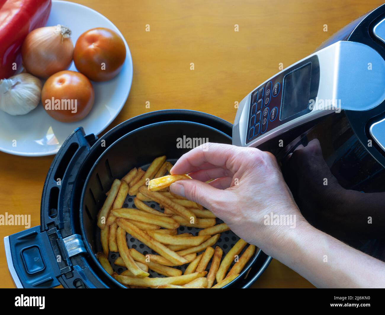 A top view of a person eating a french fry from an air fryer Stock ...