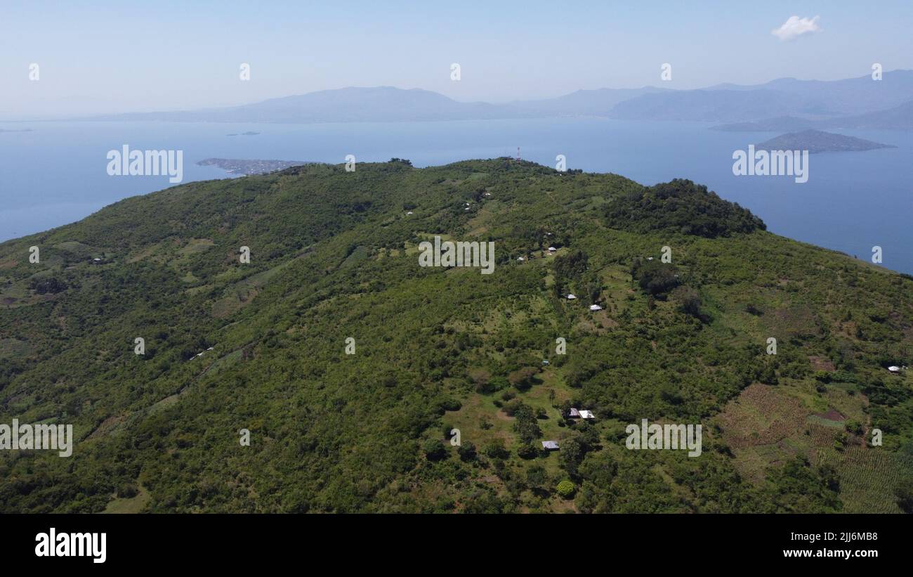 An aerial view of a green-covered mountain top with a sea in the ...