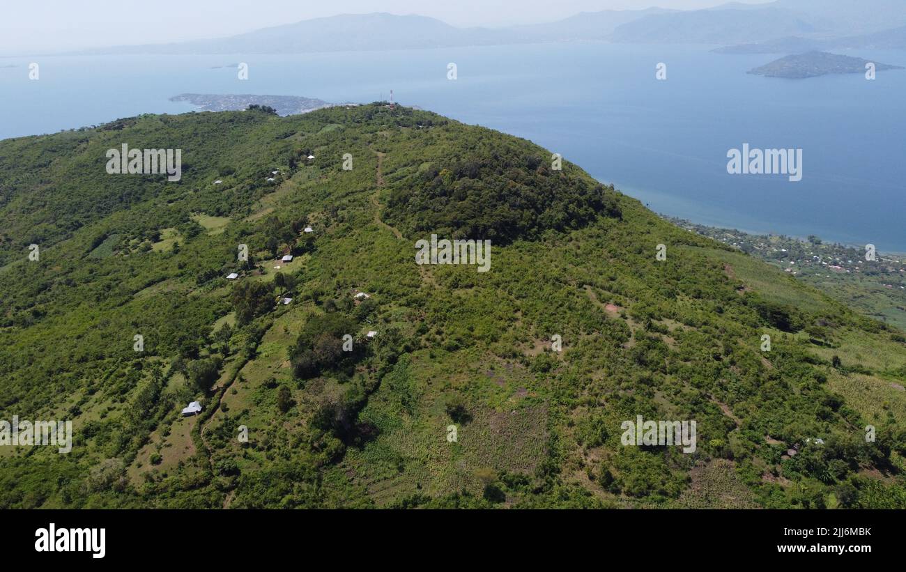 An aerial view of a green-covered mountain top with a sea in the ...