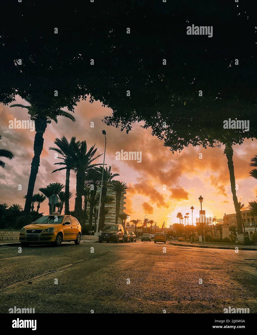 A vertical low angle shot from the street of cloudy orange sunset sky ...